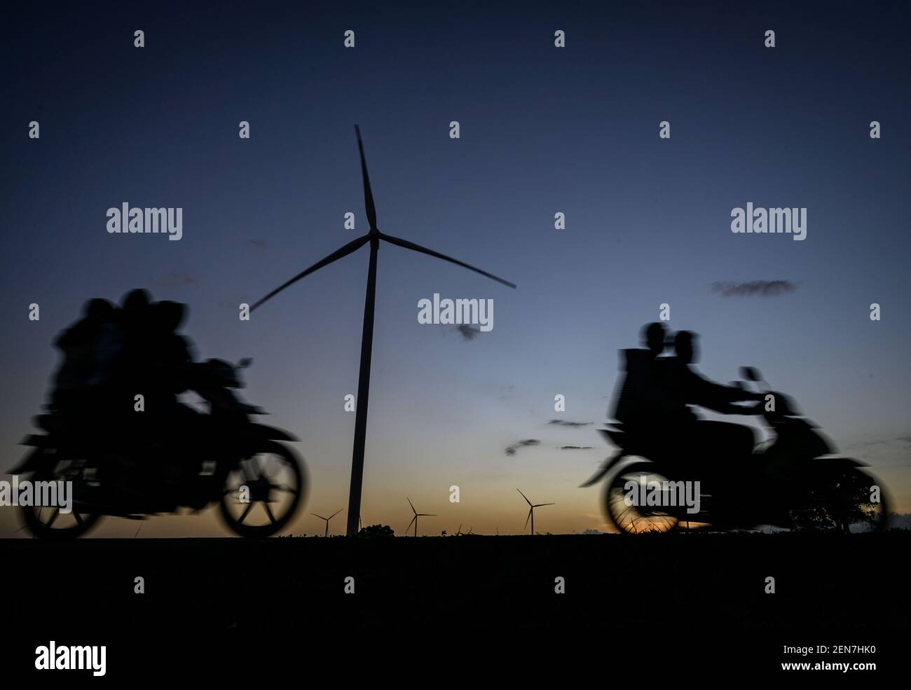 Residents ride past the turbines on Tolo 1Jeneponto wind energy power ...