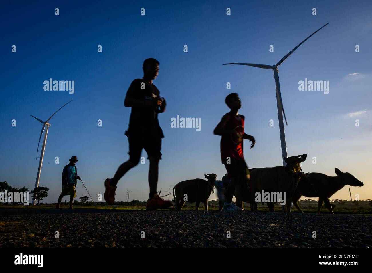Residents walk past the turbines on Tolo 1Jeneponto wind energy power ...