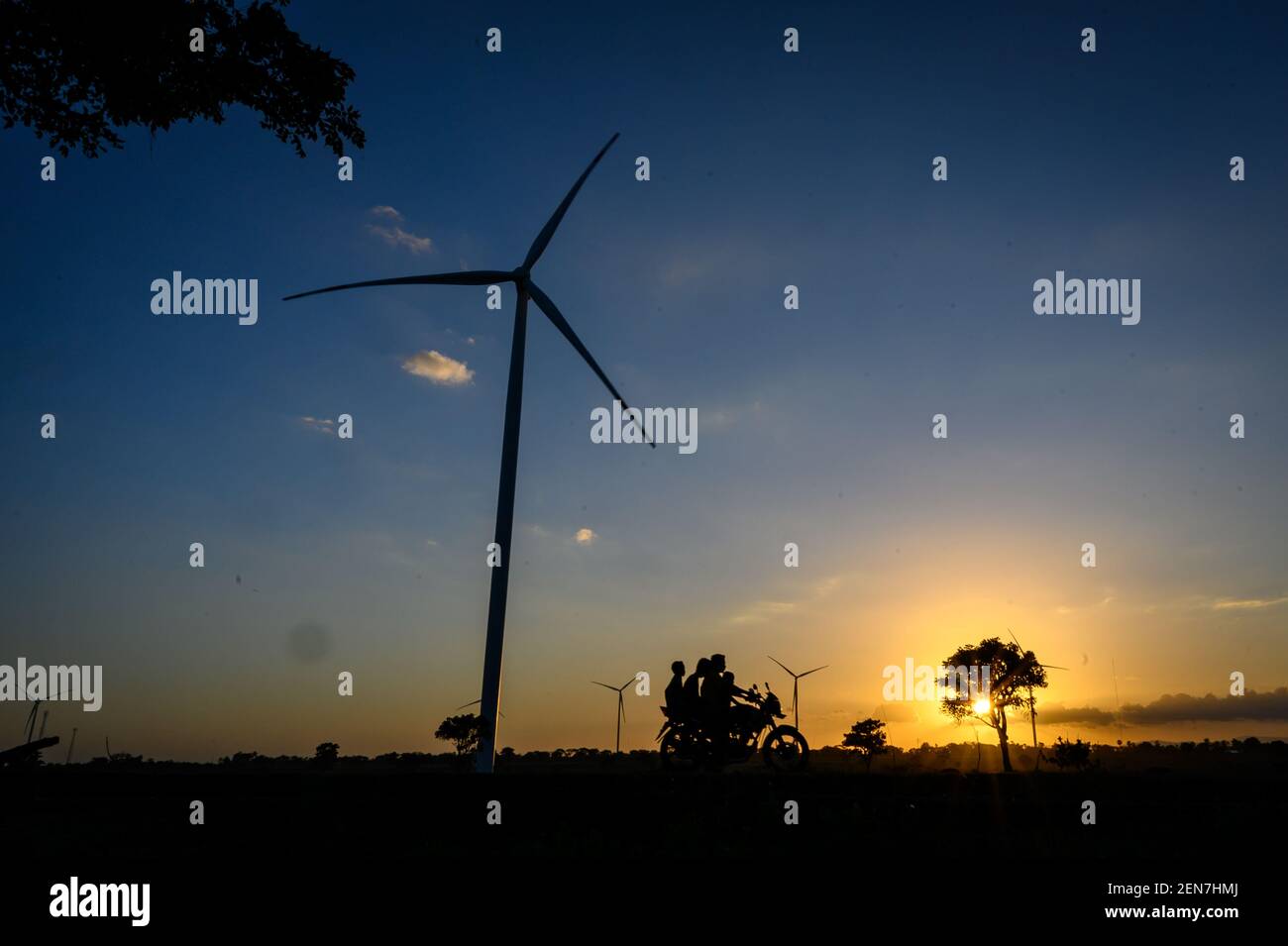 Residents ride past the turbines on Tolo 1Jeneponto wind energy power ...