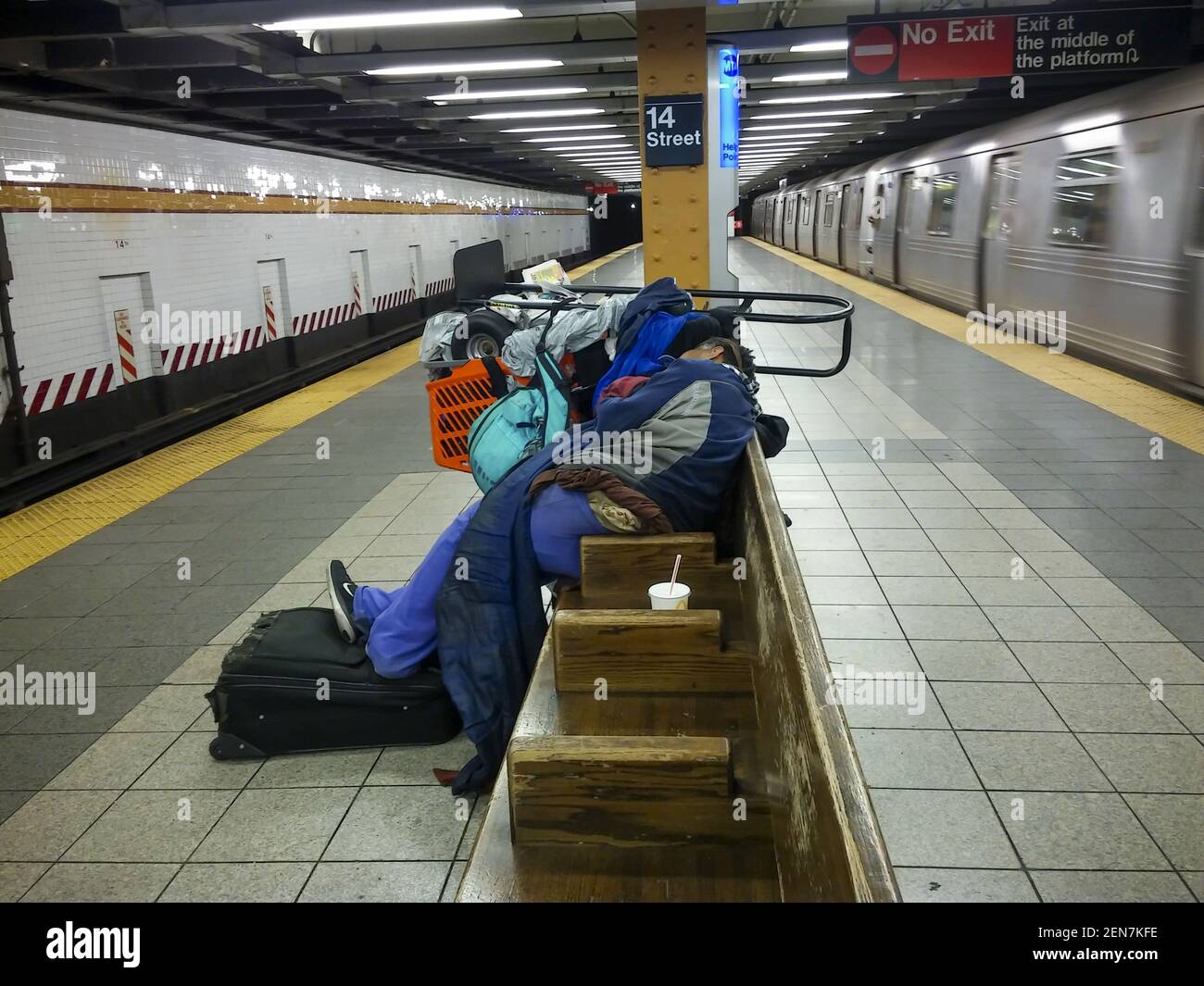 A homeless woman with her possessions sleeps on a bench in an Eighth ...