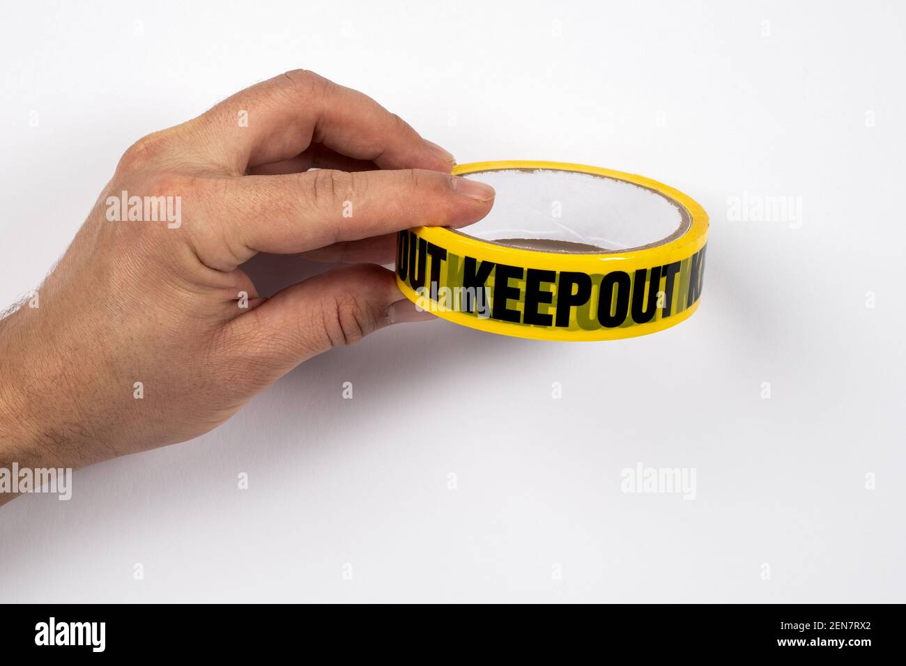KEEP OUT, yellow warning tape in a man's hands on a white background ...