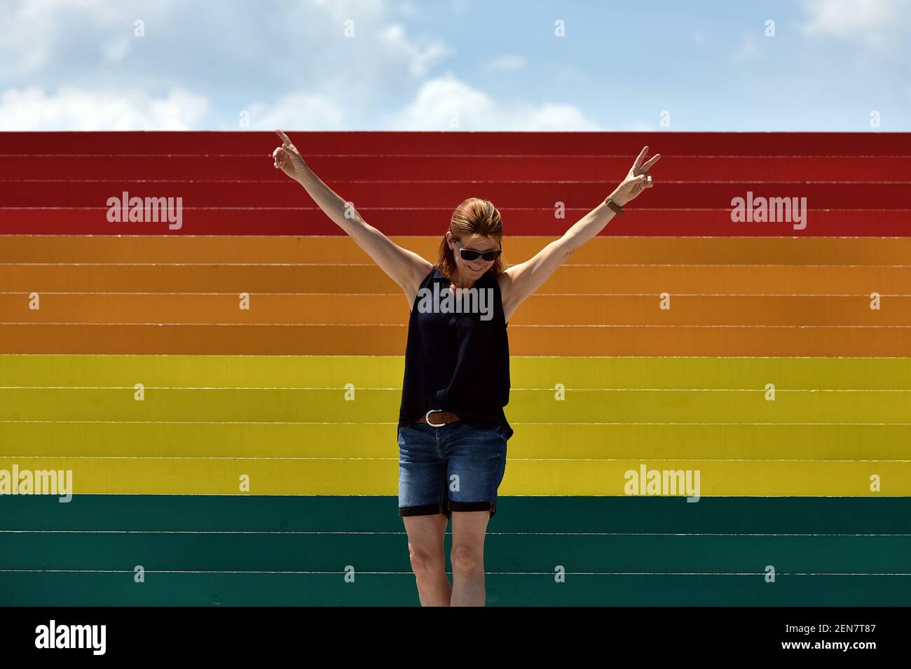 A visitor poses for pictures on LGBTQ pride flag colors painted steps ...