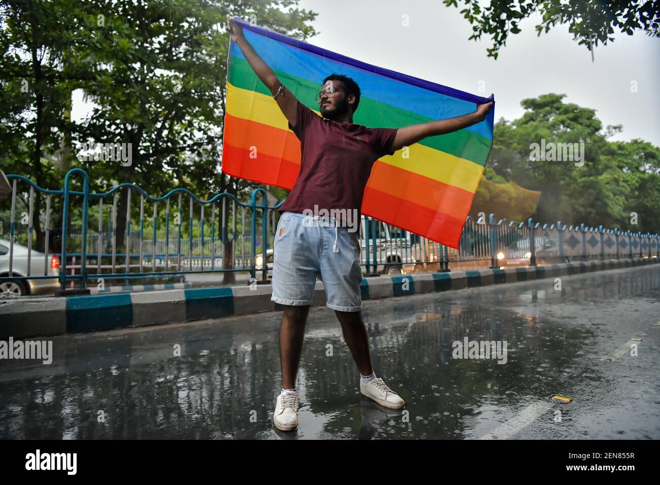 LGBTQ community member celebrates while holding a rainbow coloured flag ...