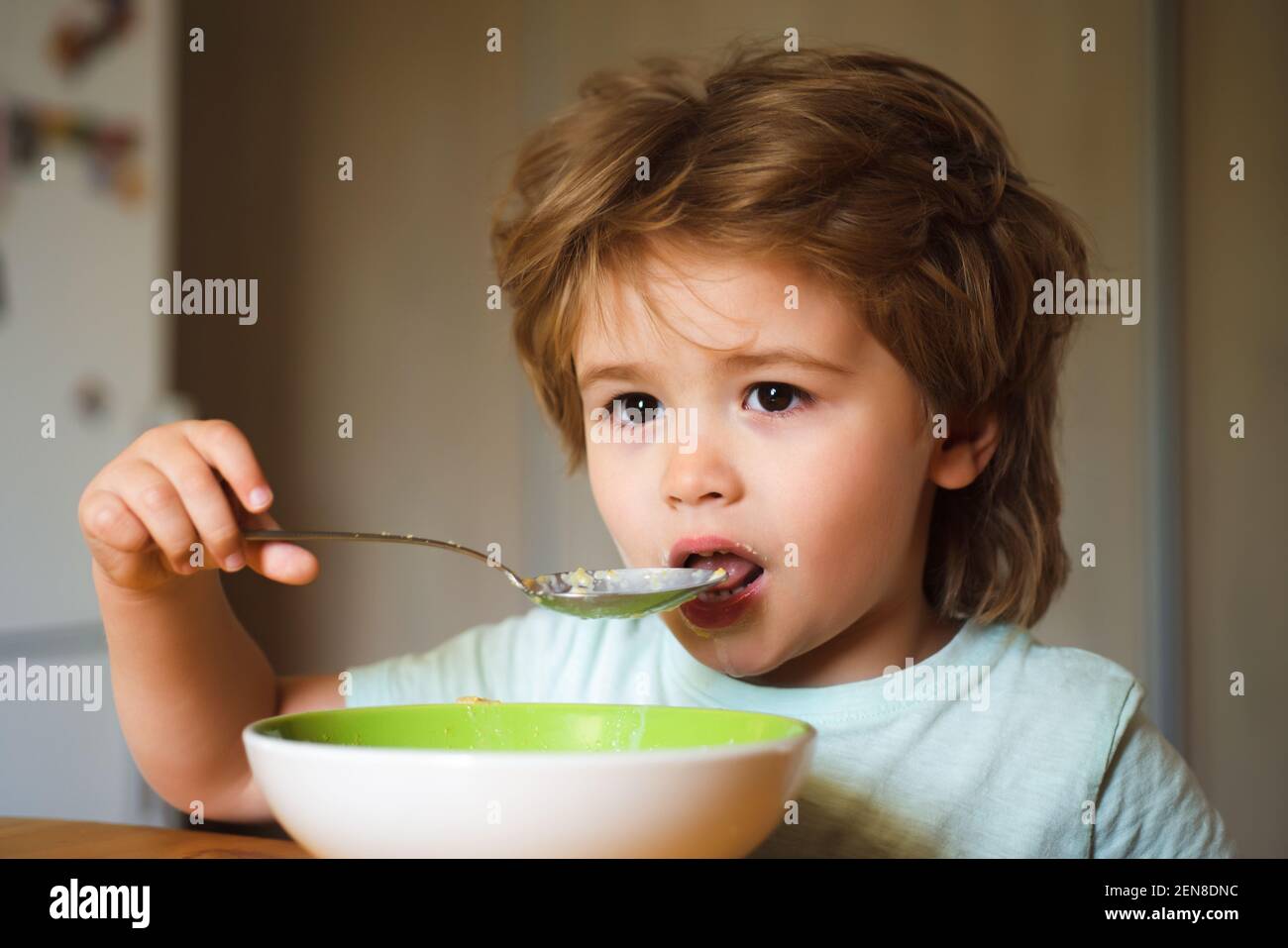 Cute child eating at home. Baby eat. Hungry little boy having breakfast ...