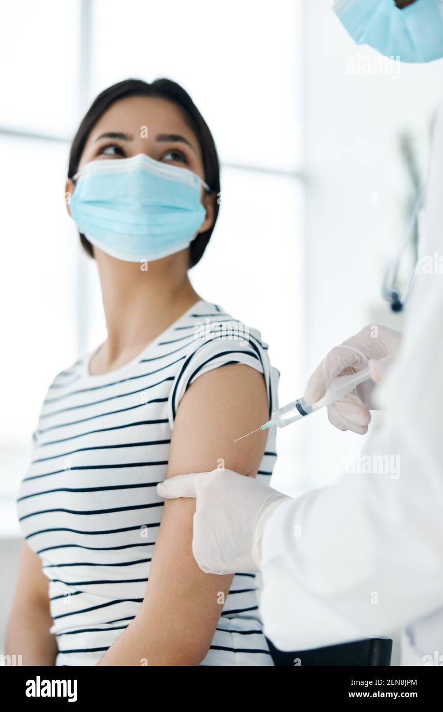 female patient in medical mask making vaccine in hospital Stock Photo ...