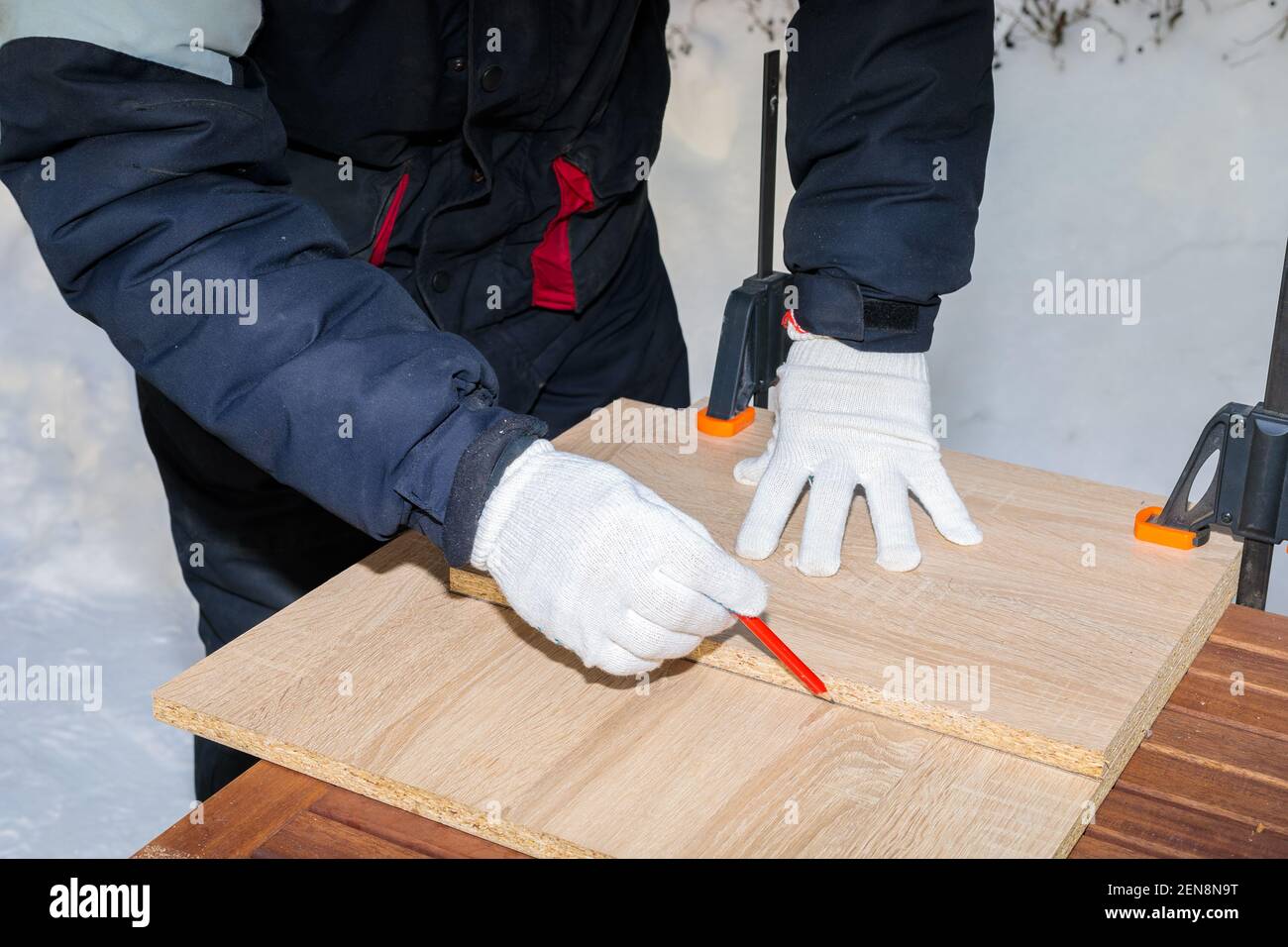 A man, a worker, marks it with a square and a pencil on a chipboard ...