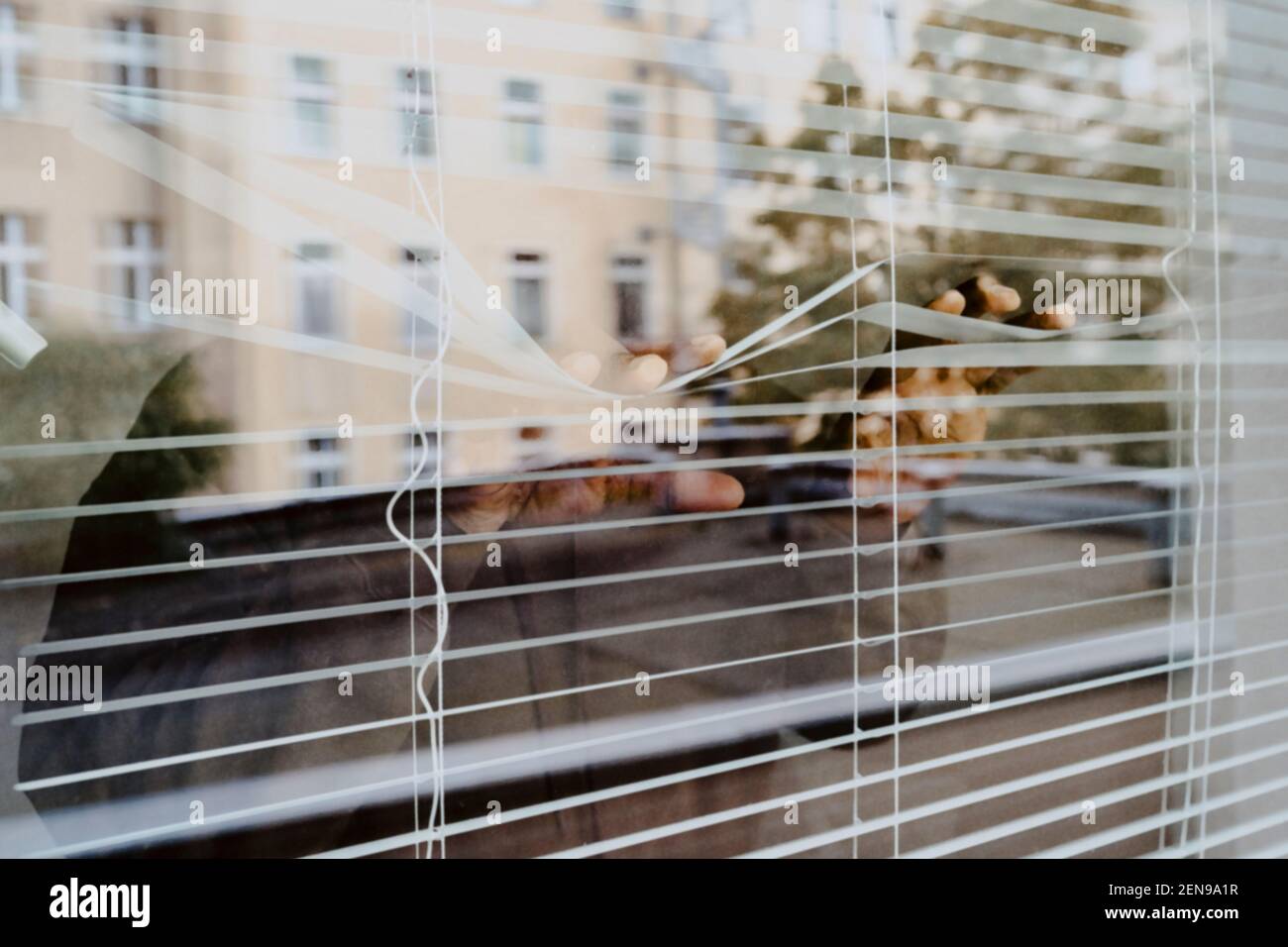 Man touching window blinds at home Stock Photo - Alamy