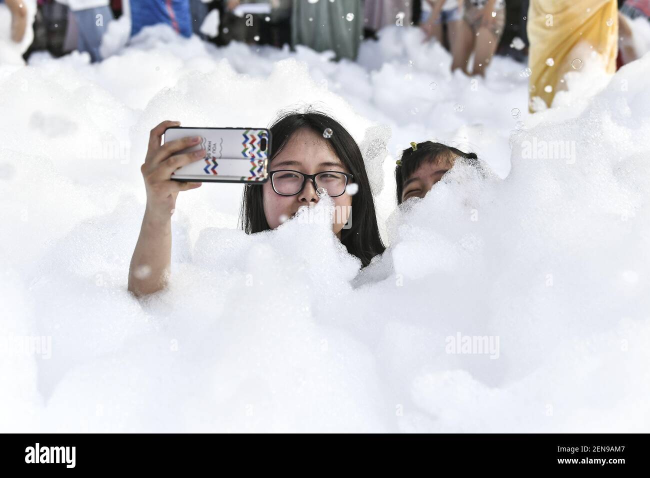 More than hundreds of tourists and local residents enjoy a bubble run ...