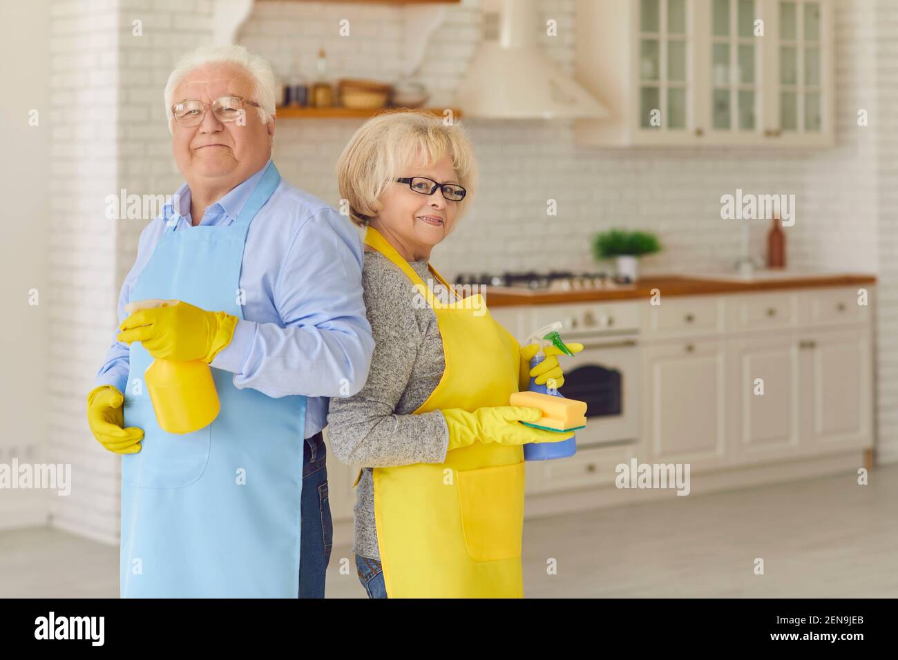 Ederly Couple Holding Cleaning Detergents And Standing With Their Backs