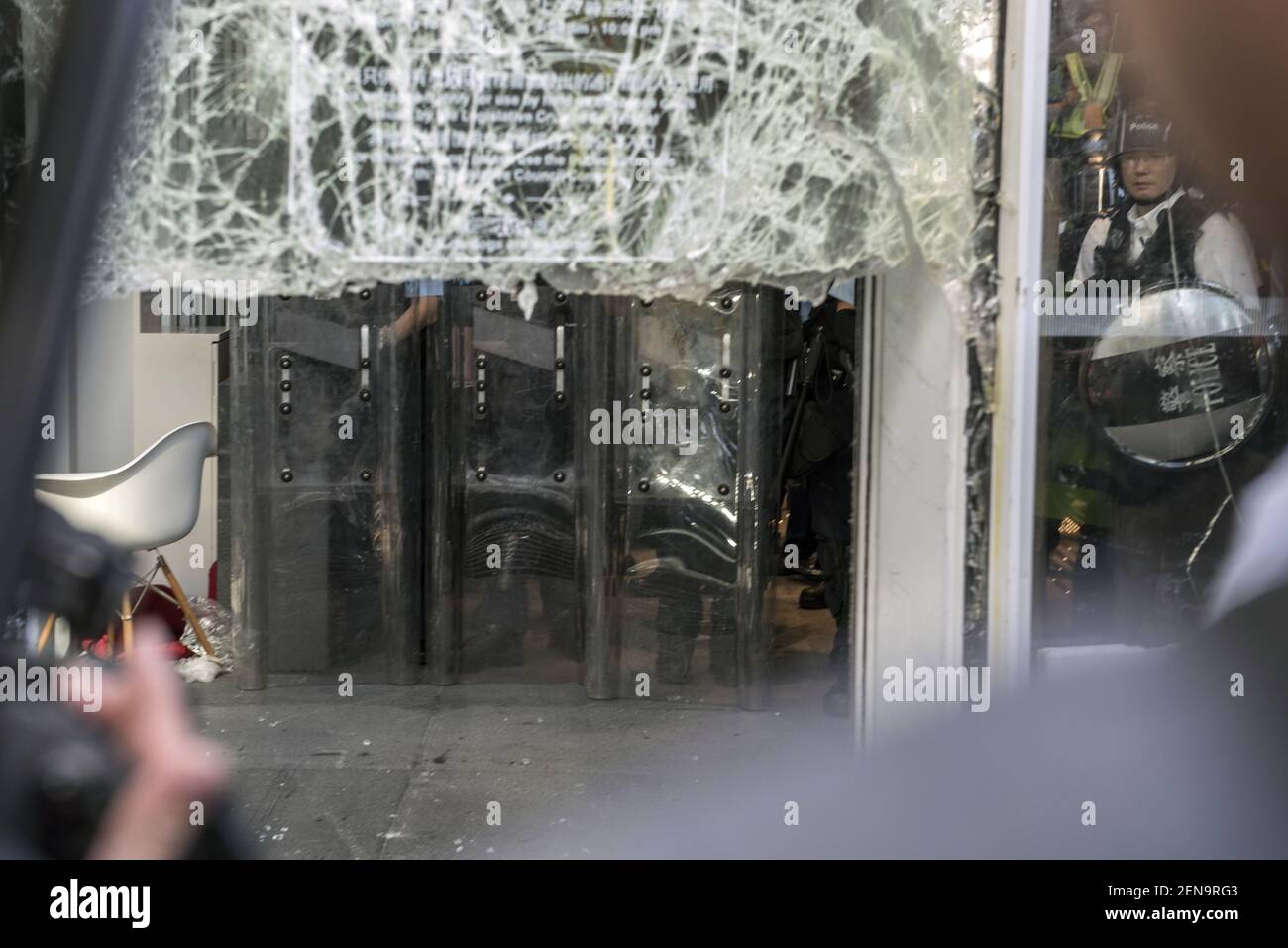 Hong Kong riot police stand guard behind a broken glass inside the ...