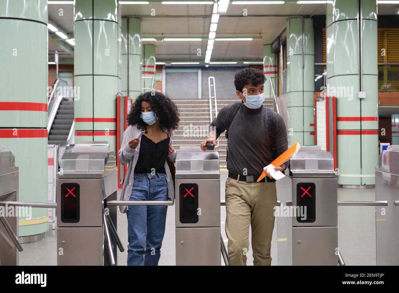 Young latin couple wearing protective face mask walking through subway ...