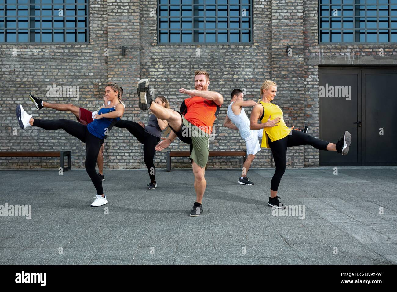 Sport enthusiasts exercising leg kicks in front of a brick wall Stock ...