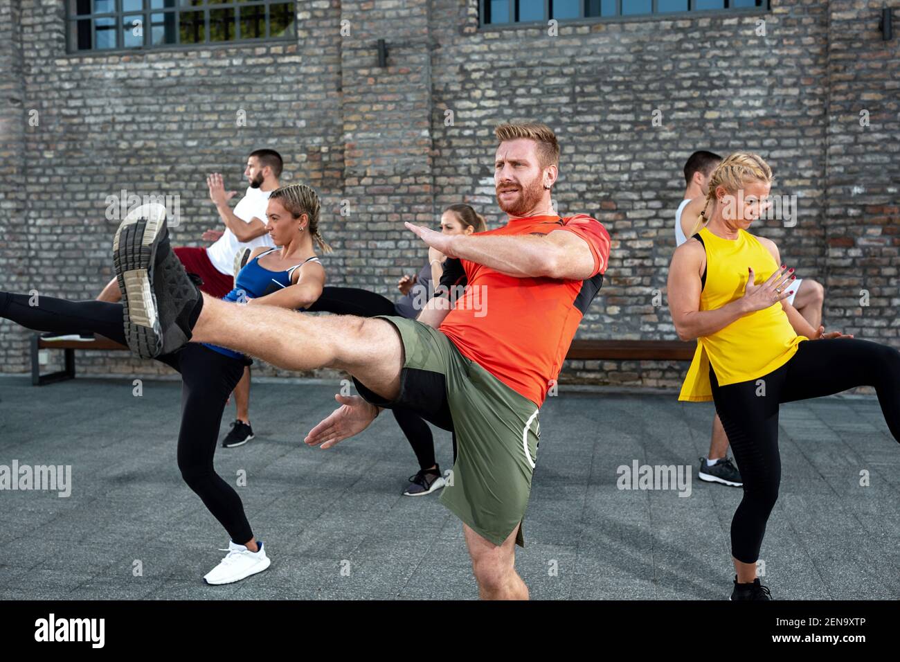 Martial art fitness coach teaching his students frontal leg kicks, leg ...