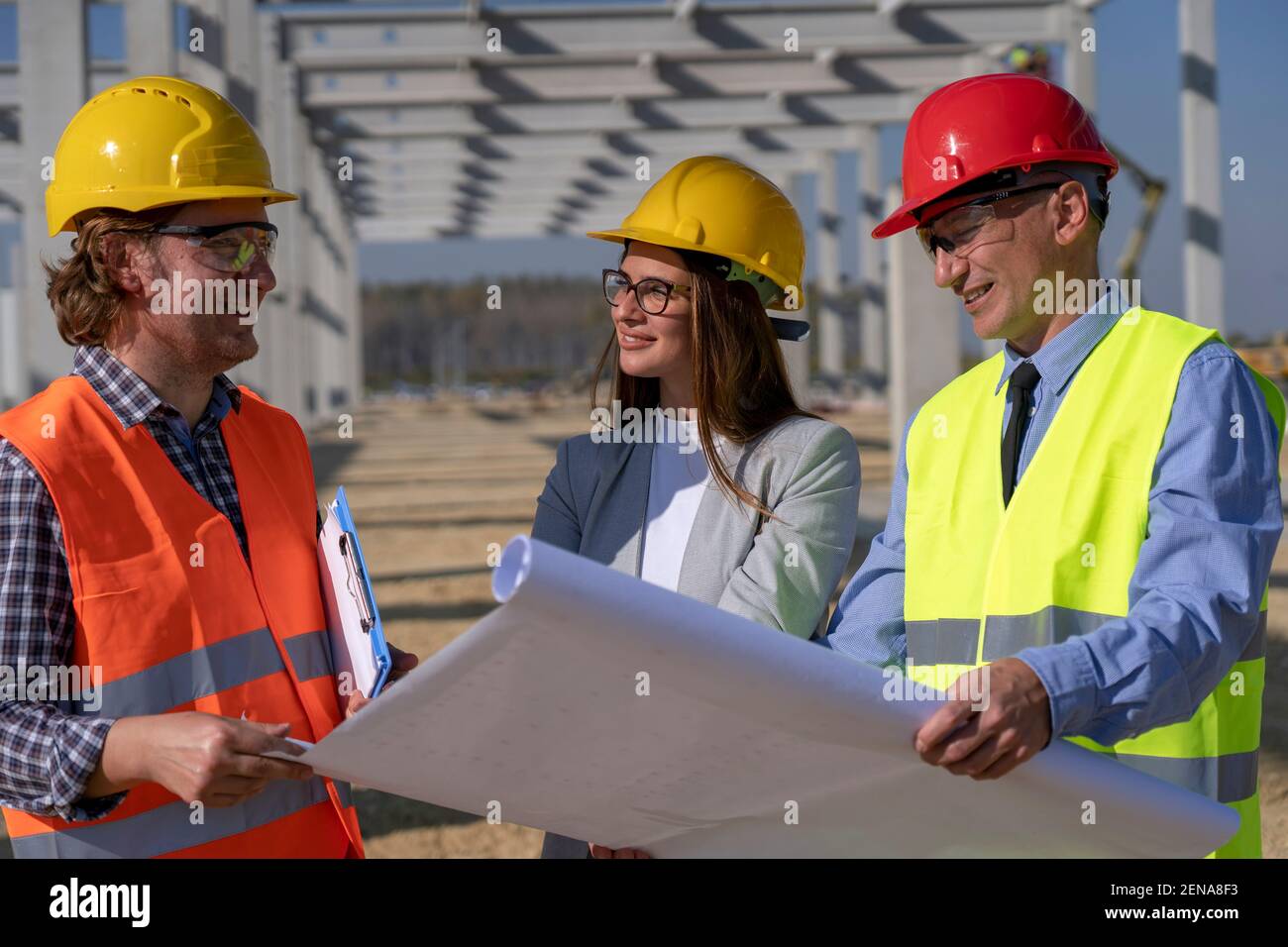 Group of Mixed Business People in Yellow and Red Hardhats Discuss a ...