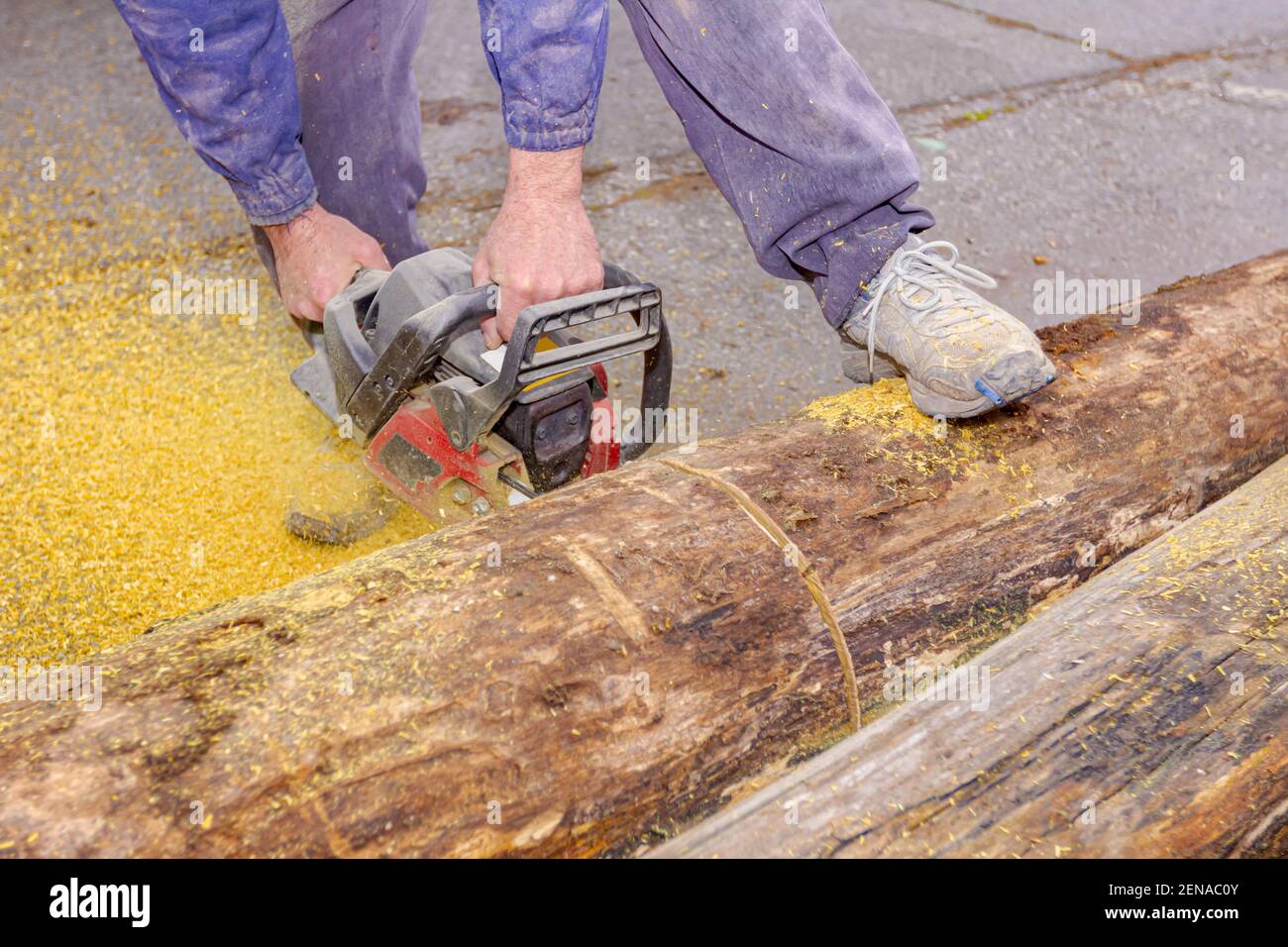 Worker at the outdoor carpentry is chopping lumbers for further ...