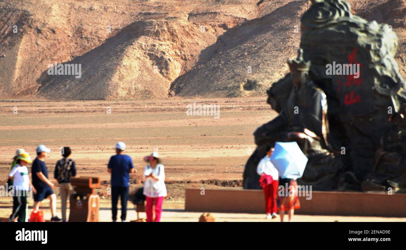 Tourists pose for photos with the landmark sculpture at the foot of the ...