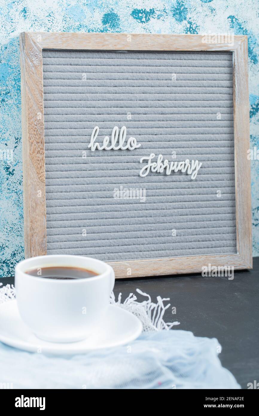 Hello february poster embedded on grey background with a cup of drink ...