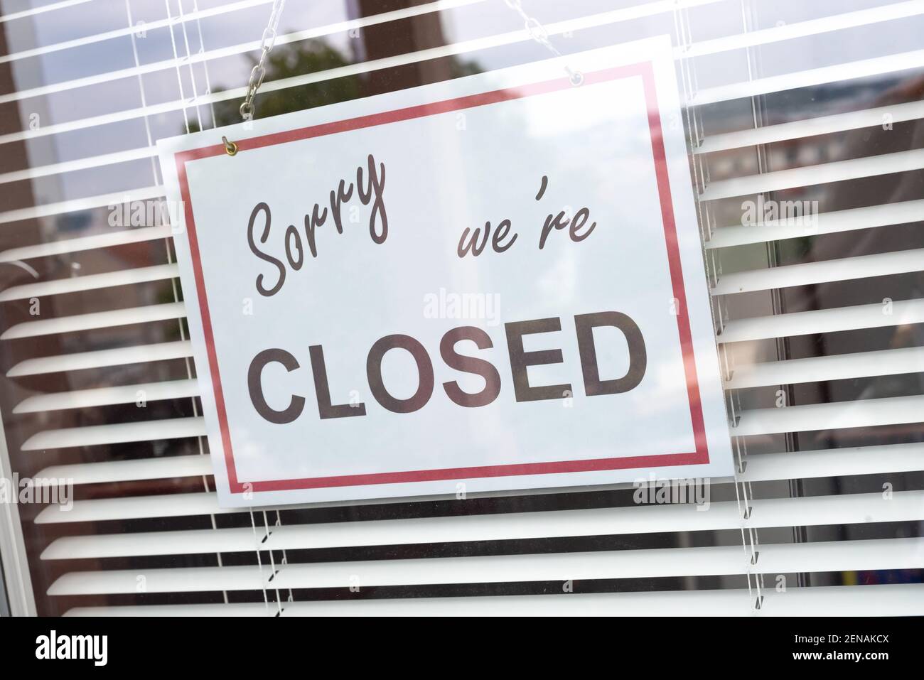 Sorry we're closed sign hanging behind a store window Stock Photo - Alamy