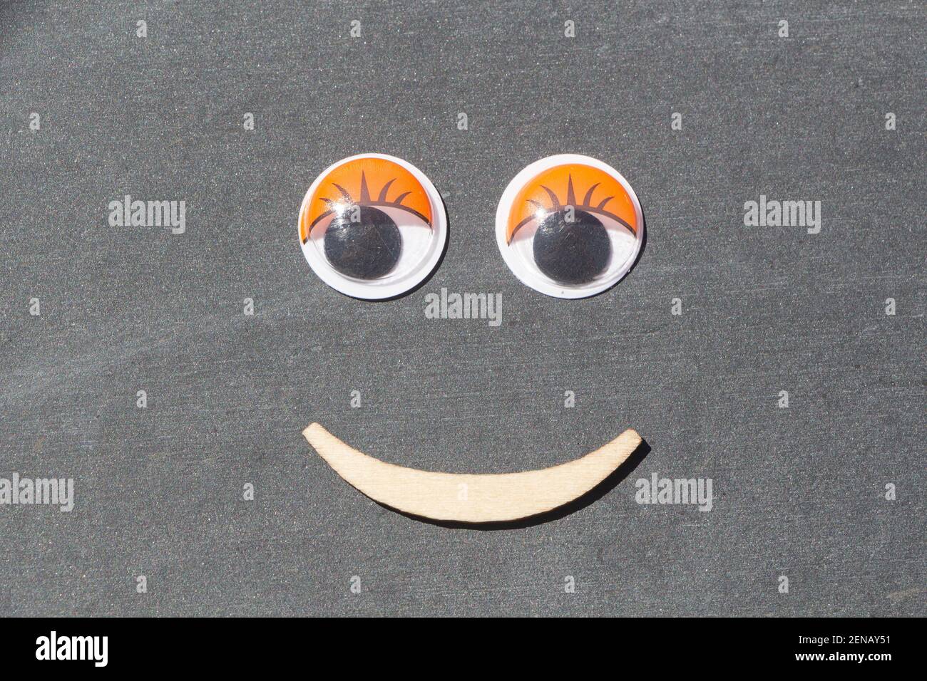 Smiling face made with plastic eyes and wooden mouth Stock Photo - Alamy