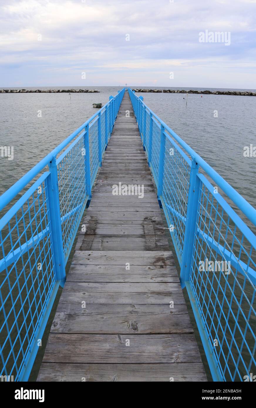 long blue bridge in the middle of the sea that leads to the pier for ...