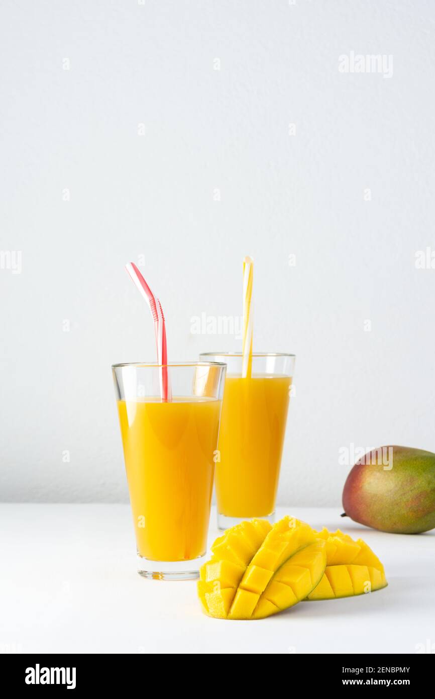 Mango juice in glasses with juice and a straw on a white background ...