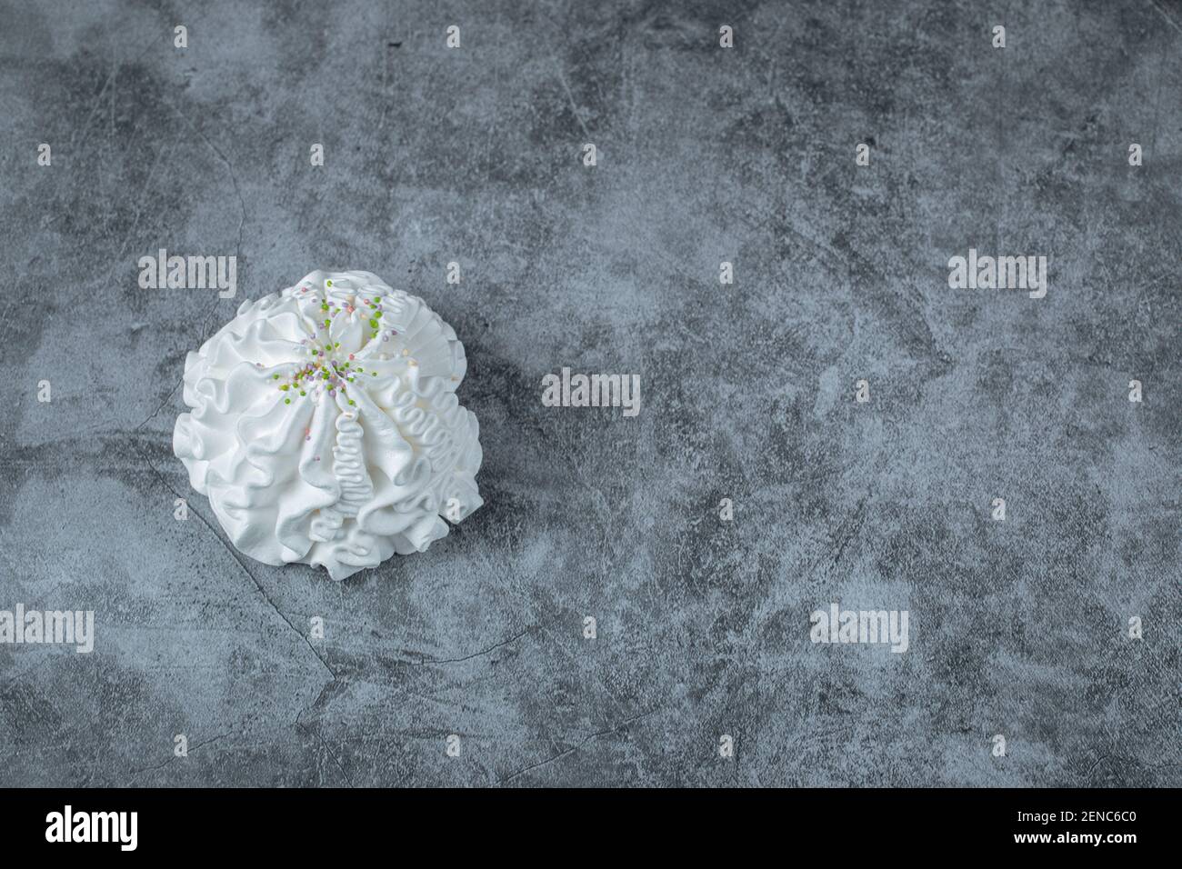 A single white isolated meringue cookie on the ground Stock Photo - Alamy