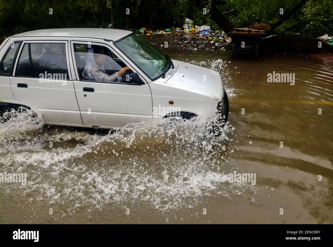 A vehicle moves through a waterlogged road during the heavy rains in ...