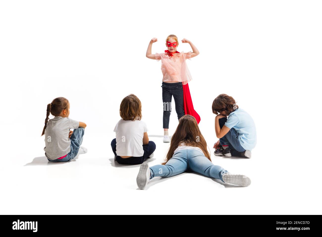 Leader. Child pretending to be a superhero with her friends sitting ...
