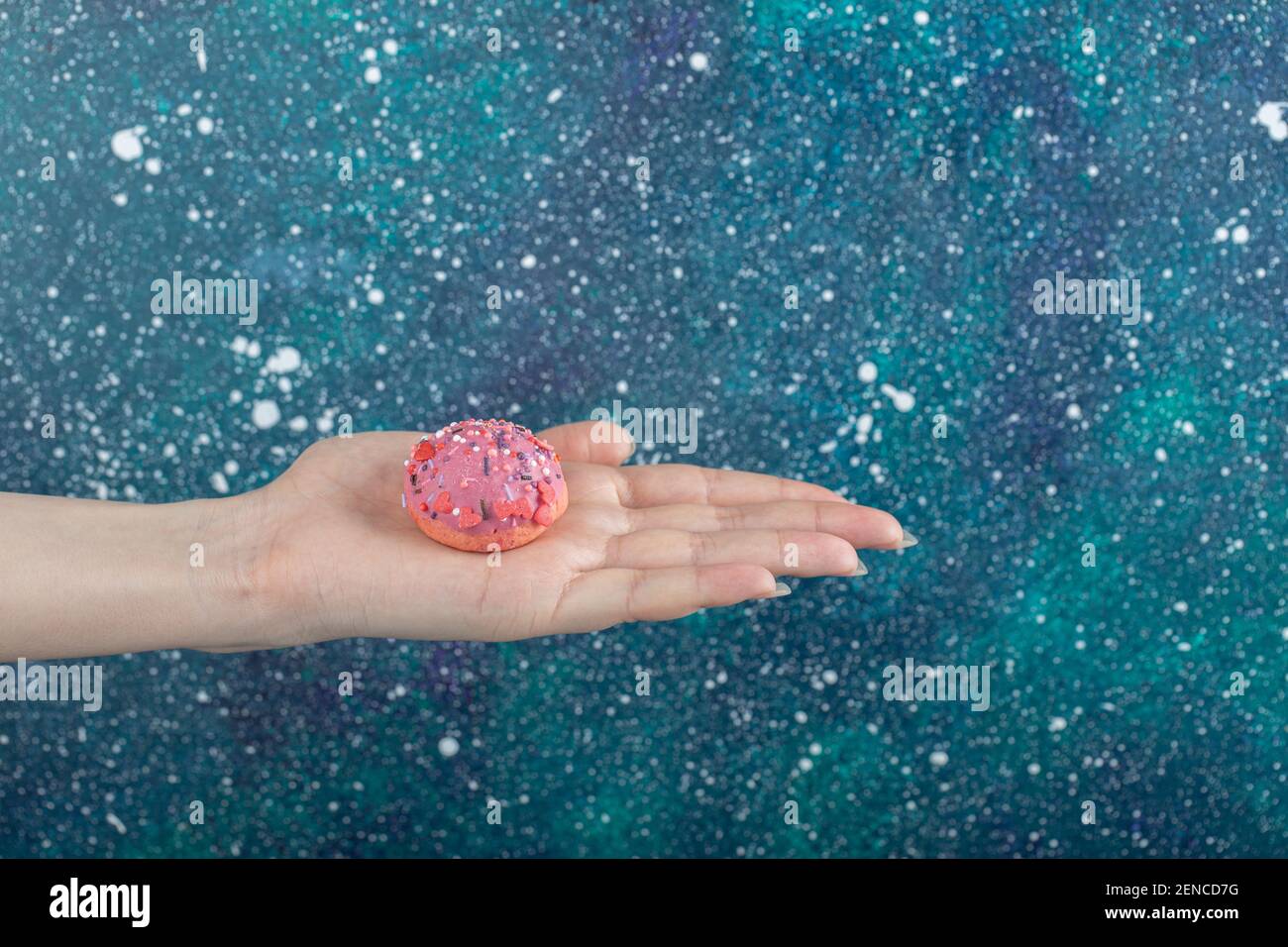 Female hand holding pink cookie with sprinkles Stock Photo - Alamy