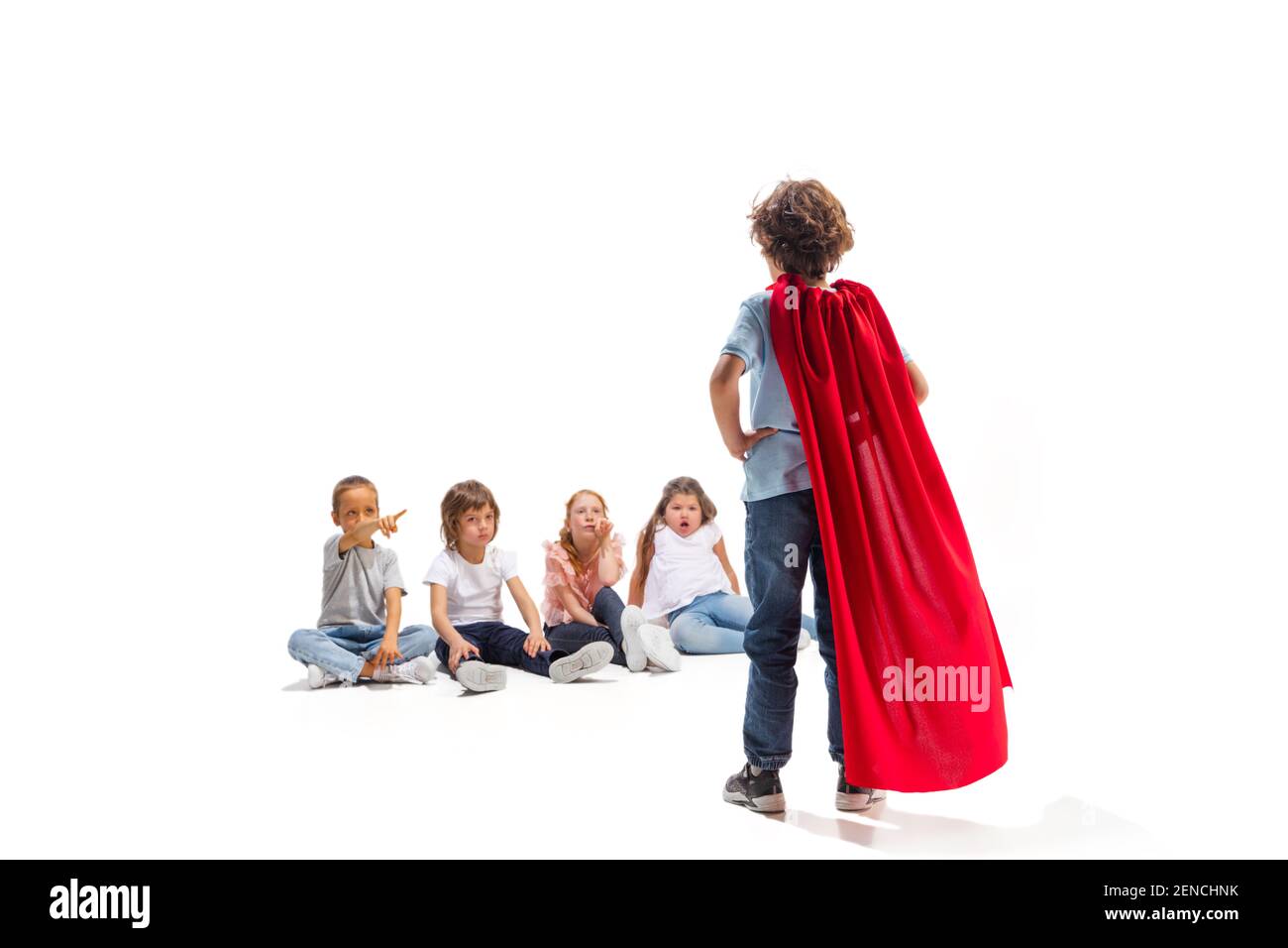 Power. Child pretending to be a superhero with his friends sitting ...