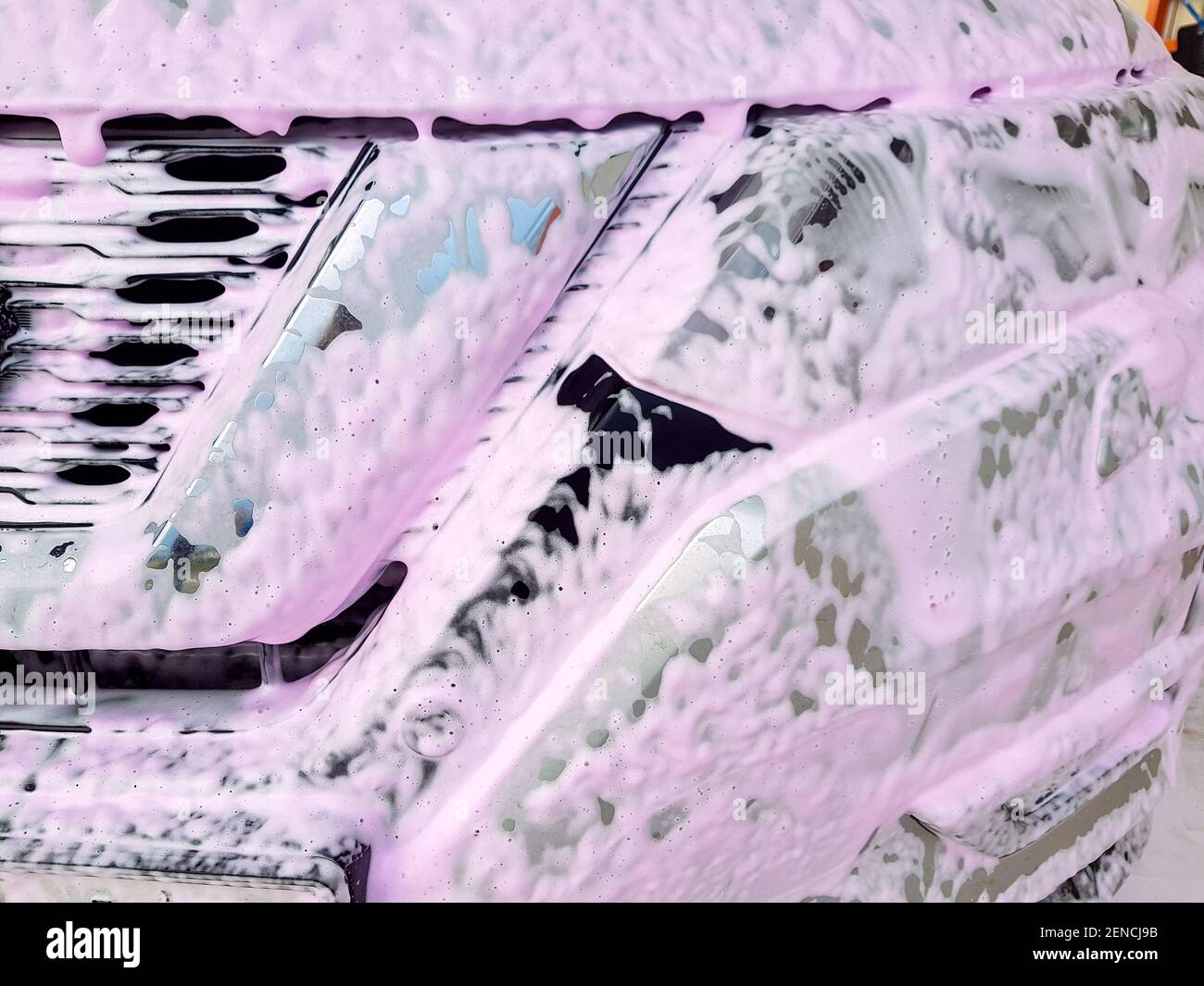 dirty car radiator grille and headlight covered with foam for washing ...