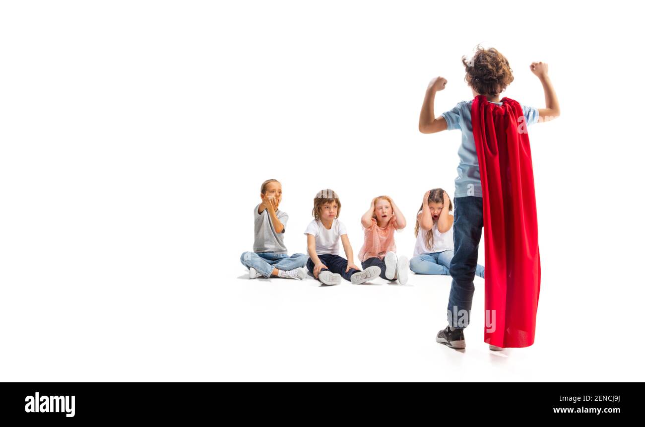 Power. Child pretending to be a superhero with his friends sitting ...