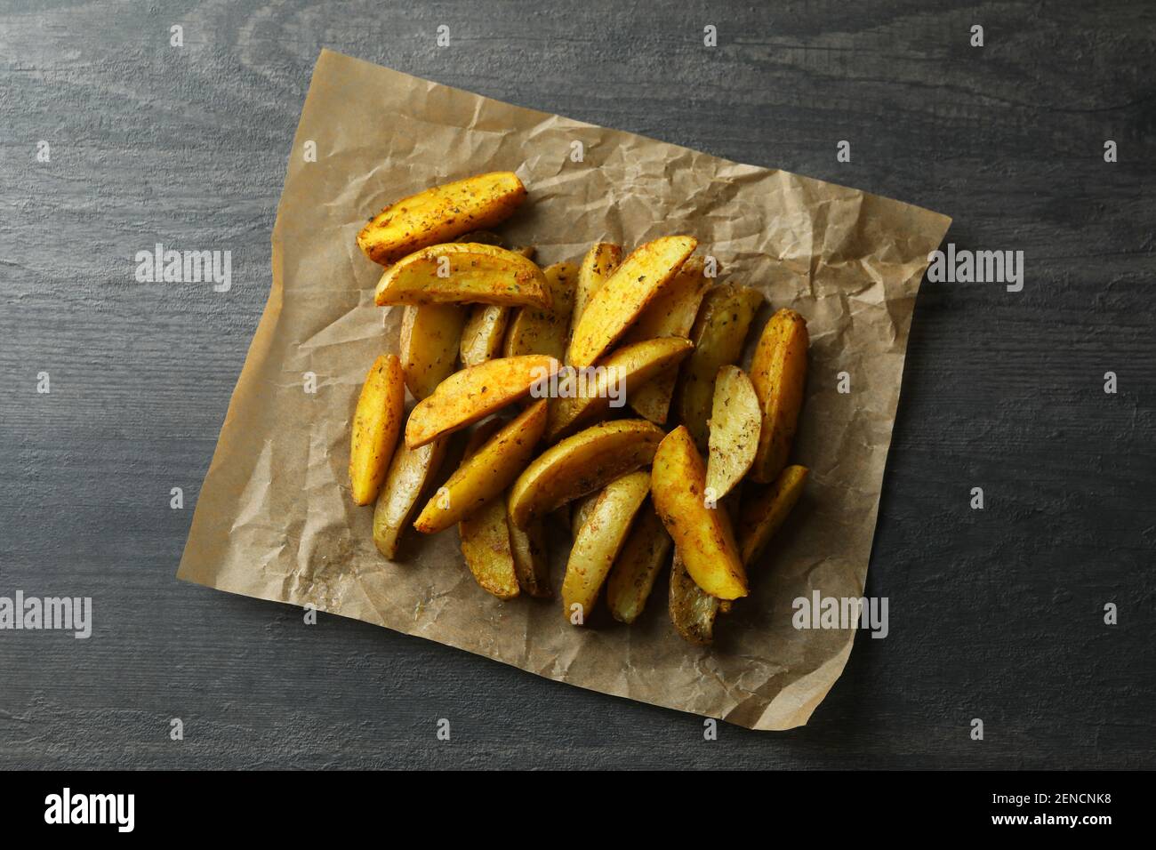 Baking paper with potato wedges on dark textured background Stock Photo ...