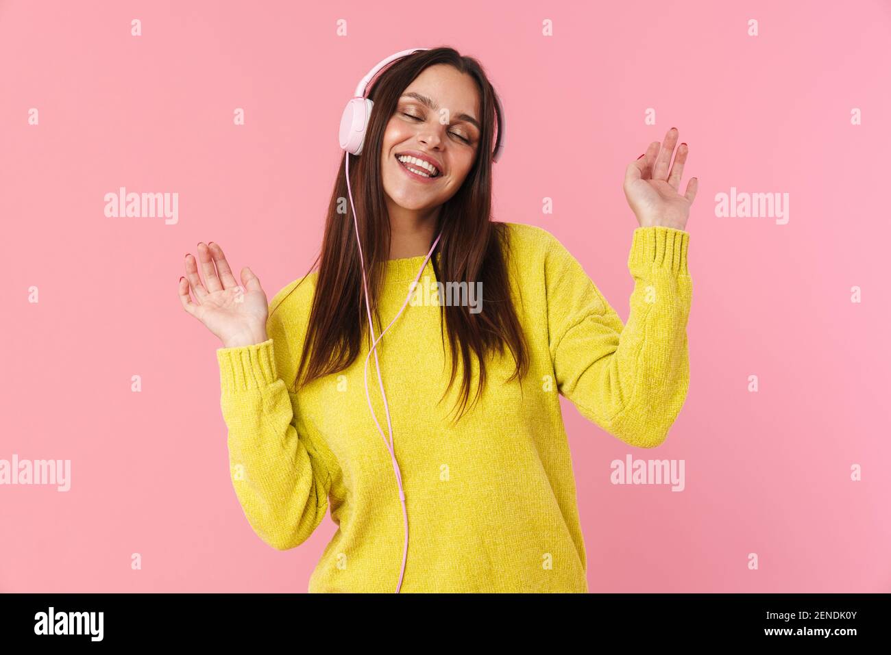 Joyful nice girl dancing while listening music with headphones isolated ...