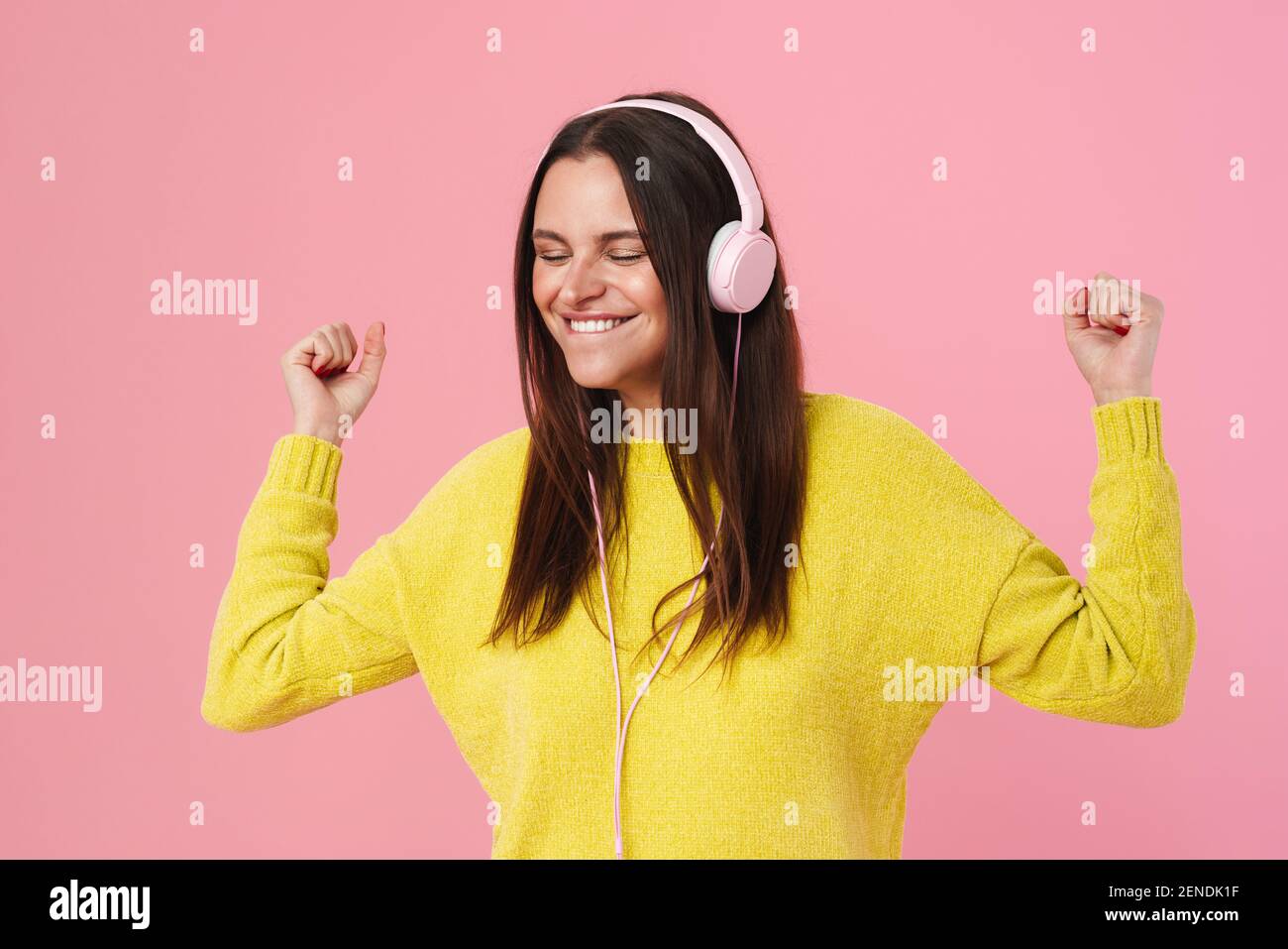 Joyful nice girl dancing while listening music with headphones isolated ...