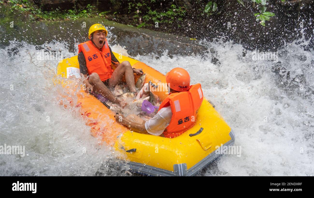 A crowd of tourists sitting on inflatable rafts jam a stream and catch ...