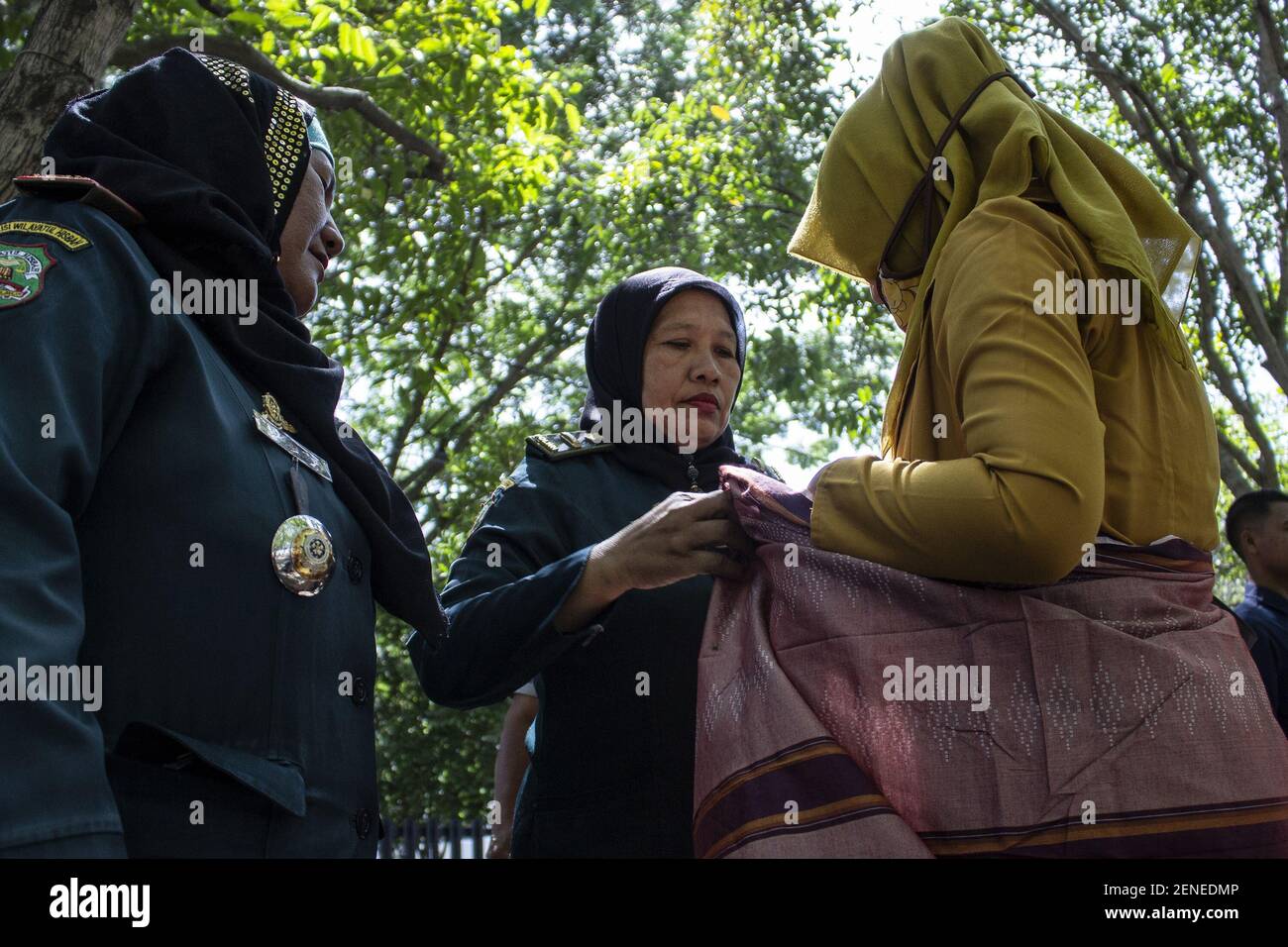 Sharia police officers dress a woman during the enforcement. Dozens of ...