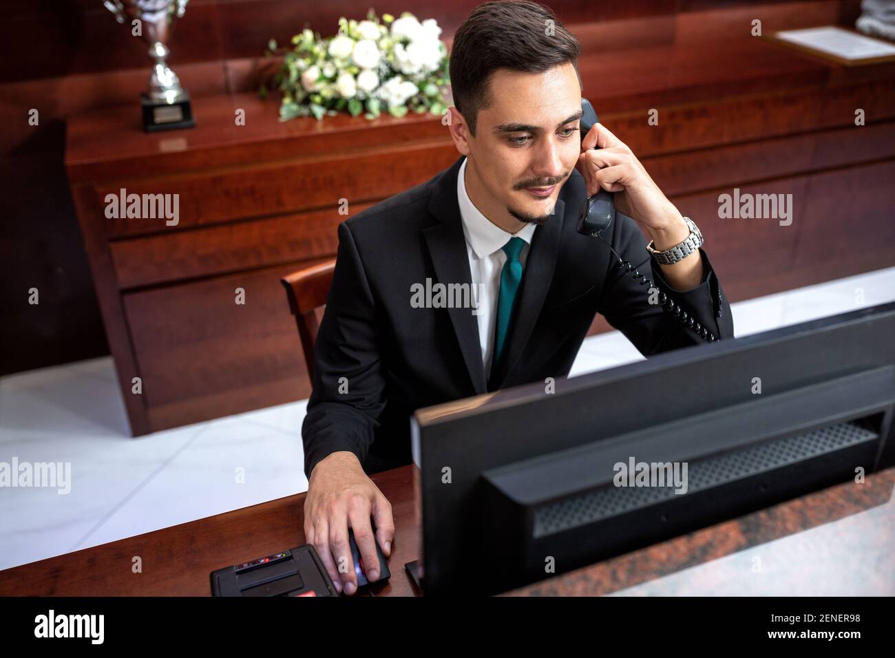Smiling receptionist tending to hotel needs, hotel service concept ...
