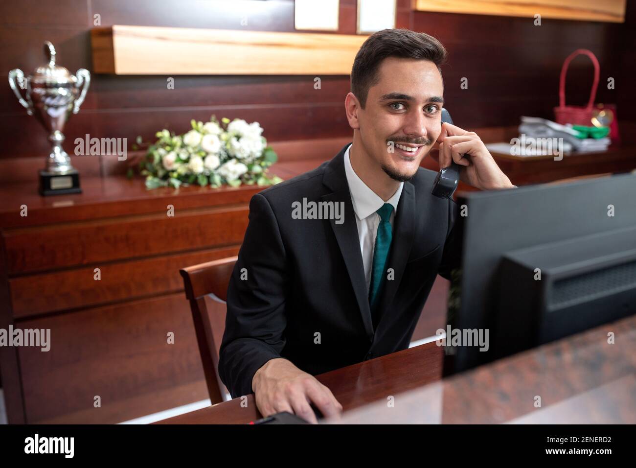 Receptionist in black suit sitting and working, reception concept Stock ...