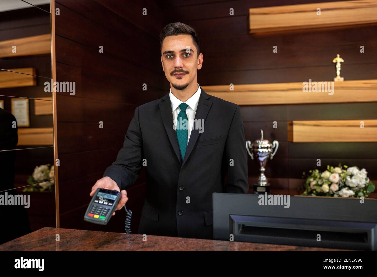 Receptionist holding a credit card reader with his right hand Stock ...