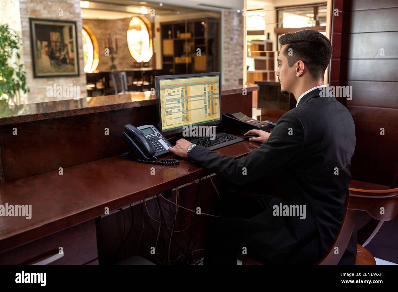 Receptionist Sitting Behind A Front Desk And Looking At His Monitor
