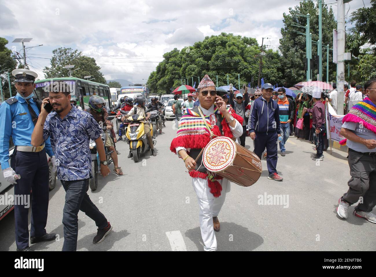 A Nepalese indigenous man dressed in a traditional attire plays a drum ...