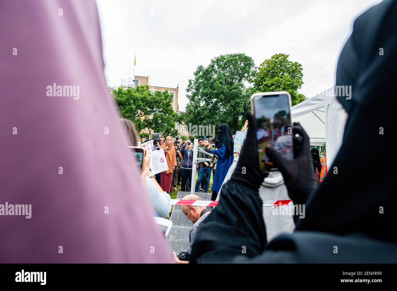 A woman wearing a niqab takes pictures of the march with her mobile ...