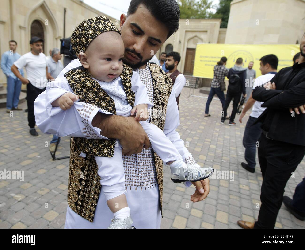 A Muslim man carries his son at the Ar-Rahma Mosque during the ...
