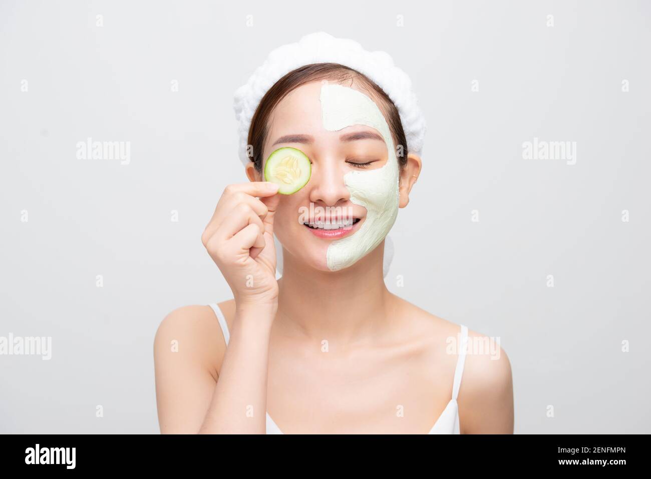 Attractive young Asian woman with clay mask and holding fruit piece ...