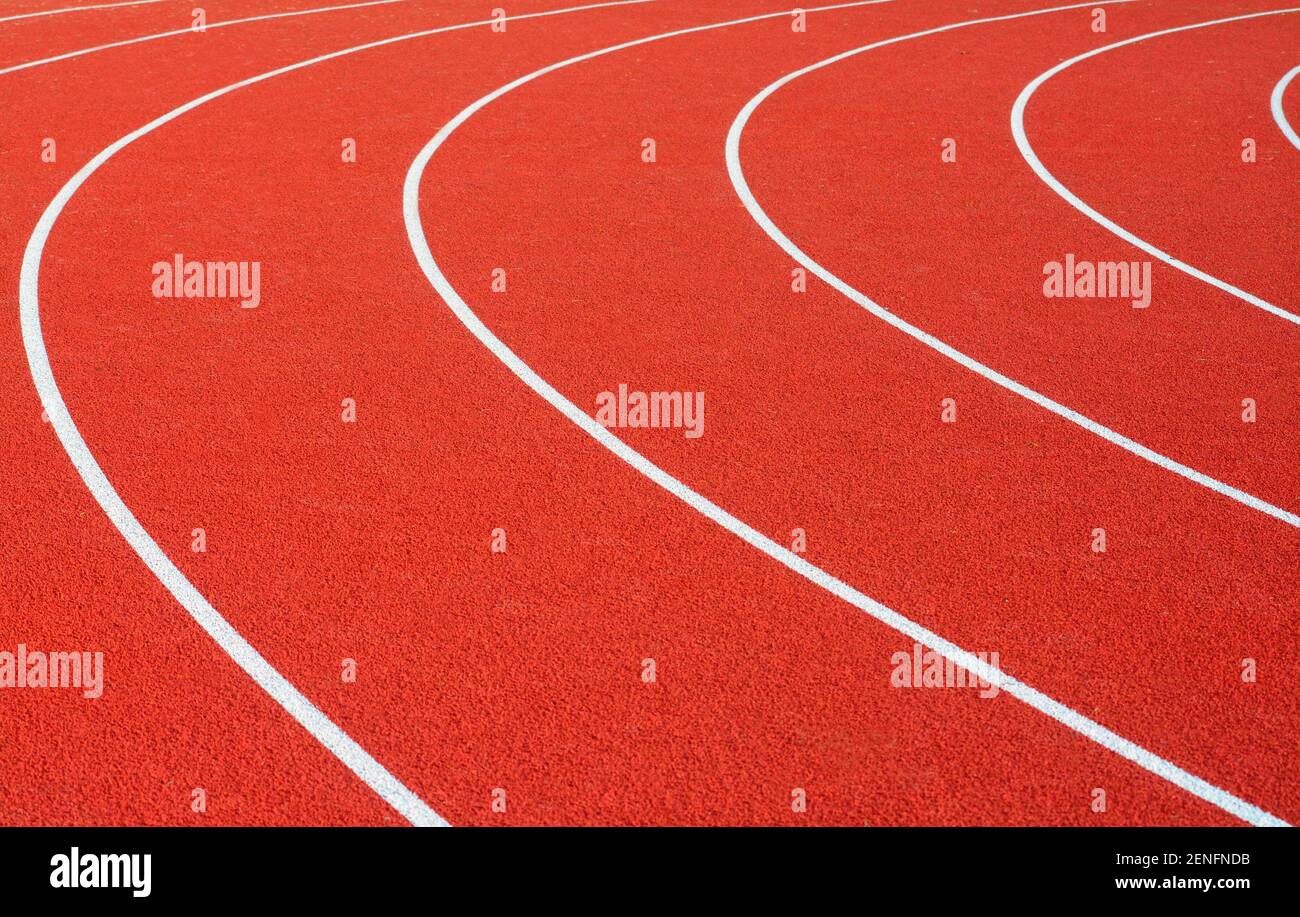 Curved white lines on a bright red artificial running track create an ... Curved white lines on a bright red artificial running track create an ...