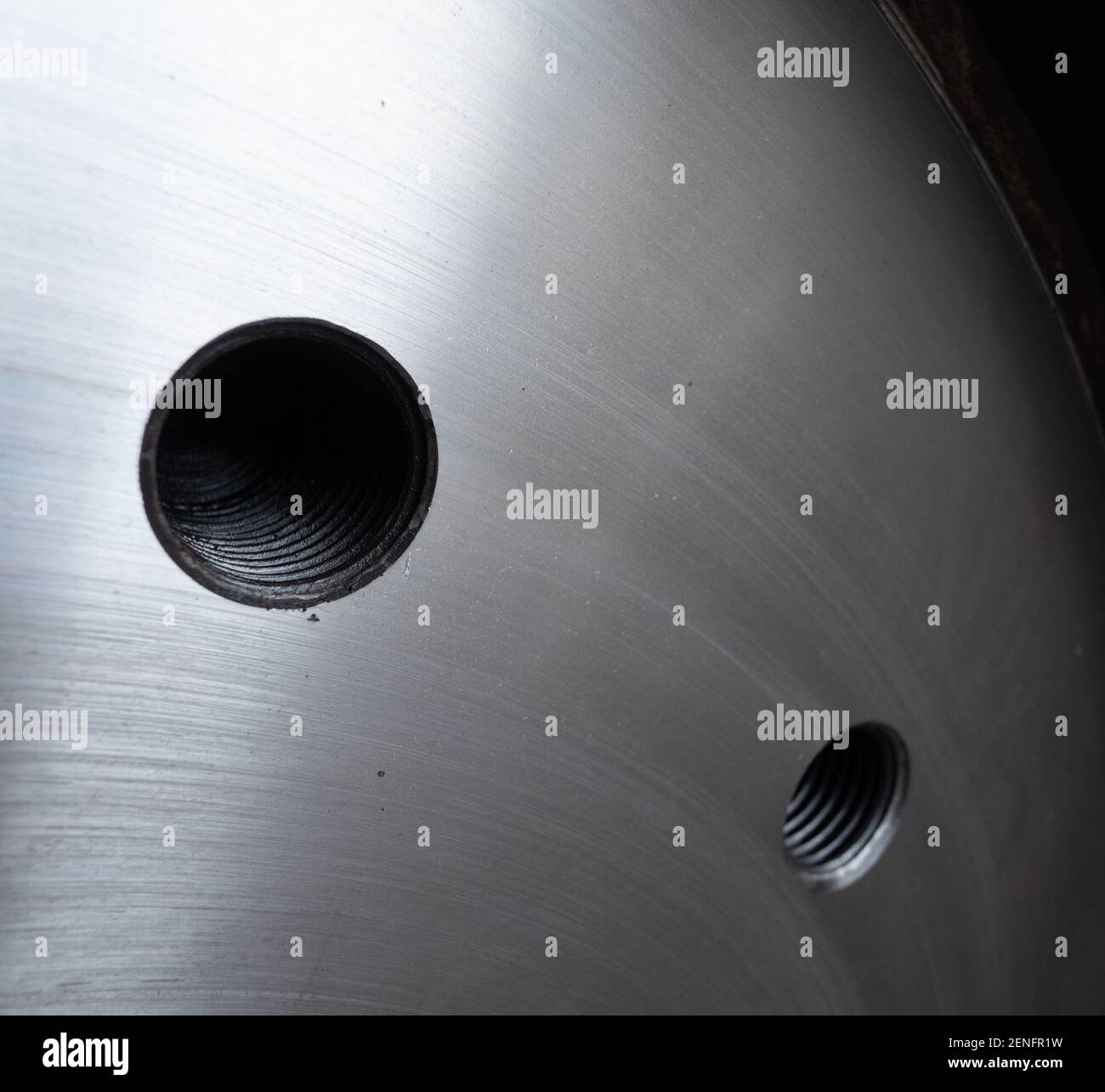 Stainless steel plate with threaded holes for bolts. Shallow depth of ...