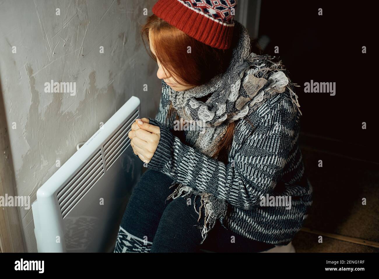 a woman is warming herself at the radiator in a cold house, problems ...