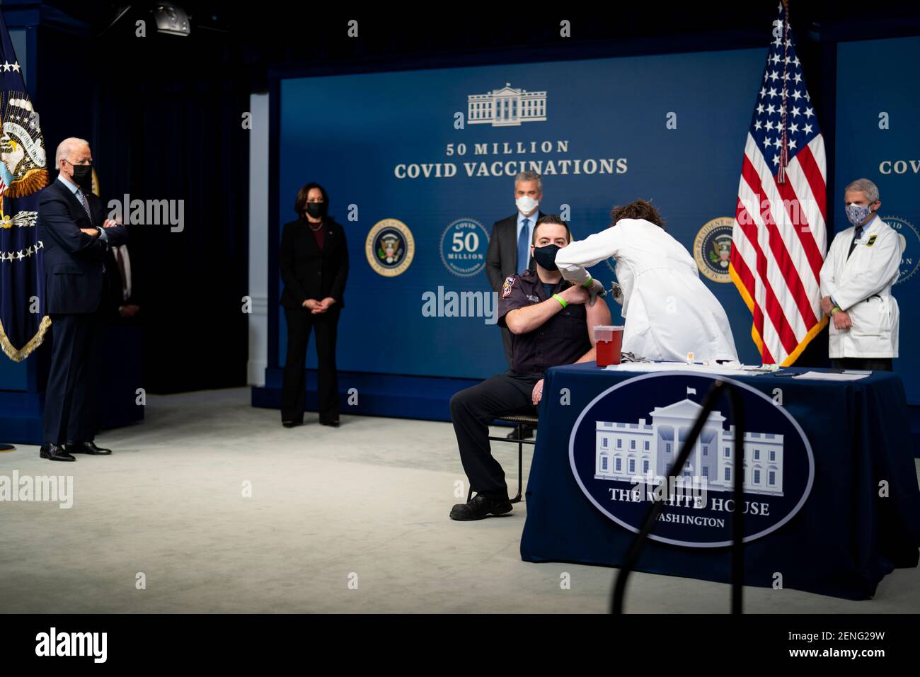President Joe Biden looks on as a nurse gives a vaccine to Corey ...