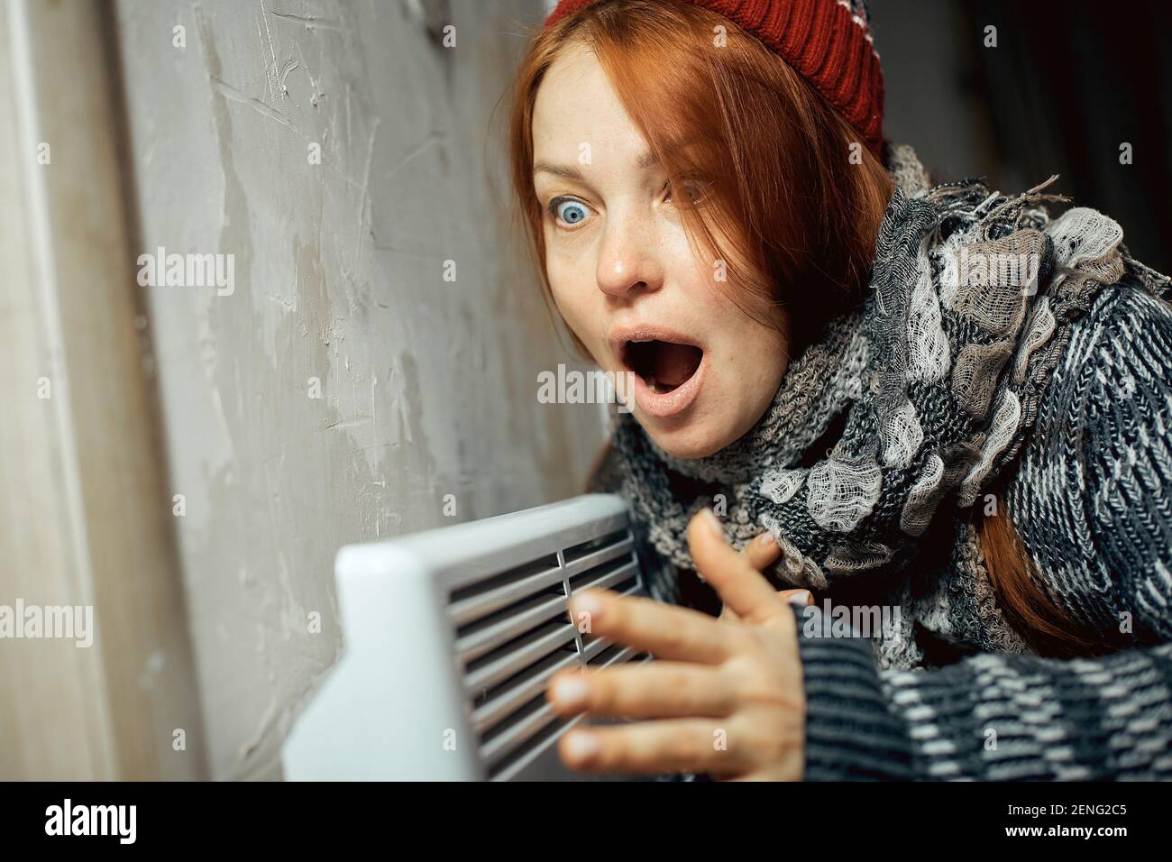 emotional woman warms up at the radiator in a cold house, problems with ...